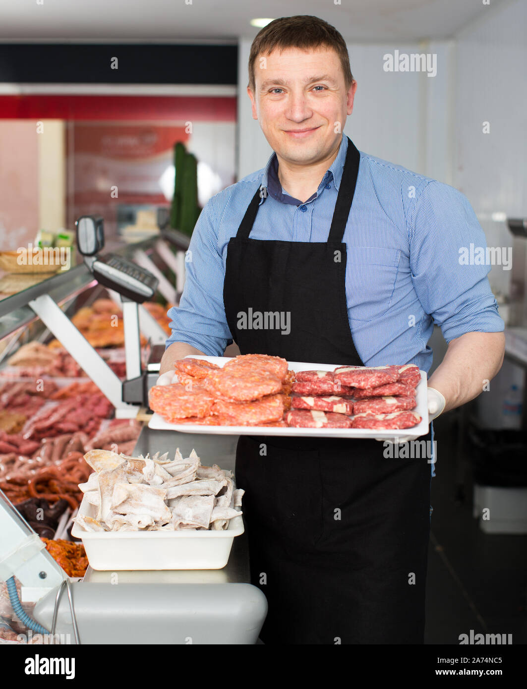 Successful owner of butcher store preparing fresh meat products for ...