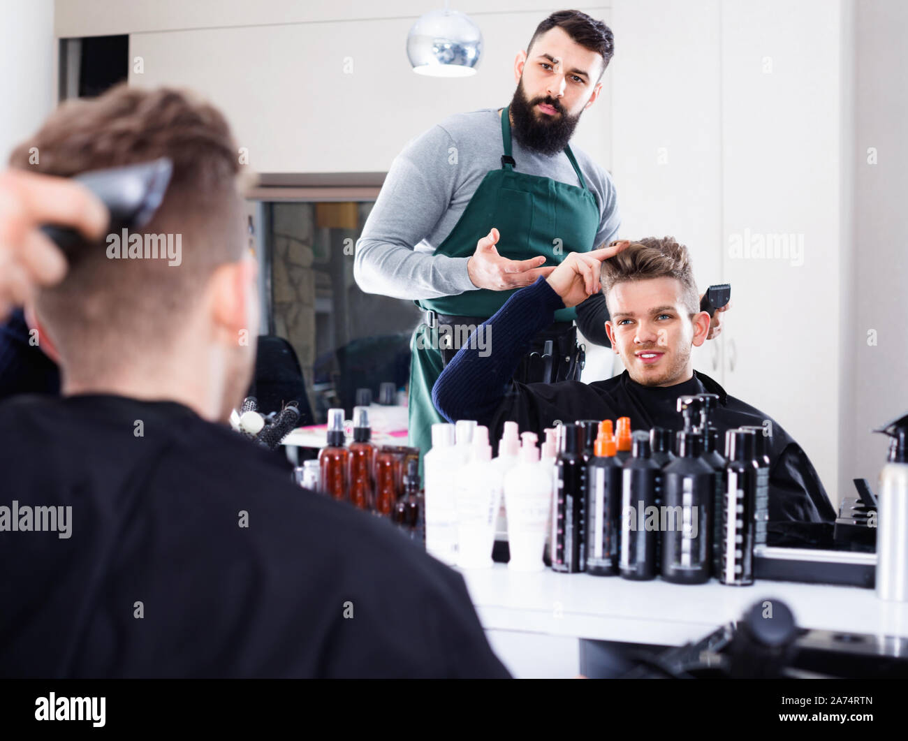 Positive smiling client making specifications about haircut with ...