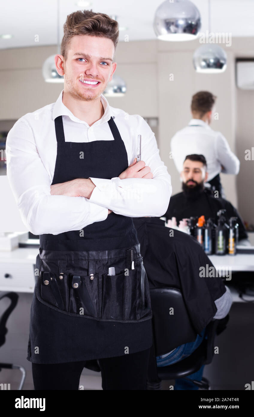 Young guy displaying his workplace and tools at hairdressing salon ...