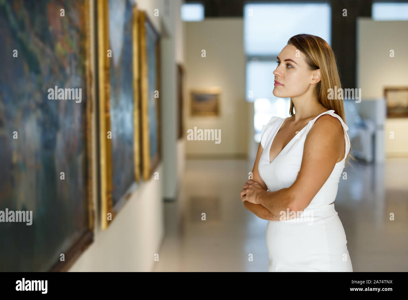 Portrait of attractive girl with guide brochure looking at paintings in ...