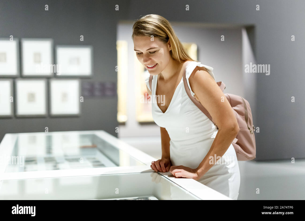 Positive woman observing with interest exhibition under glass in art ...