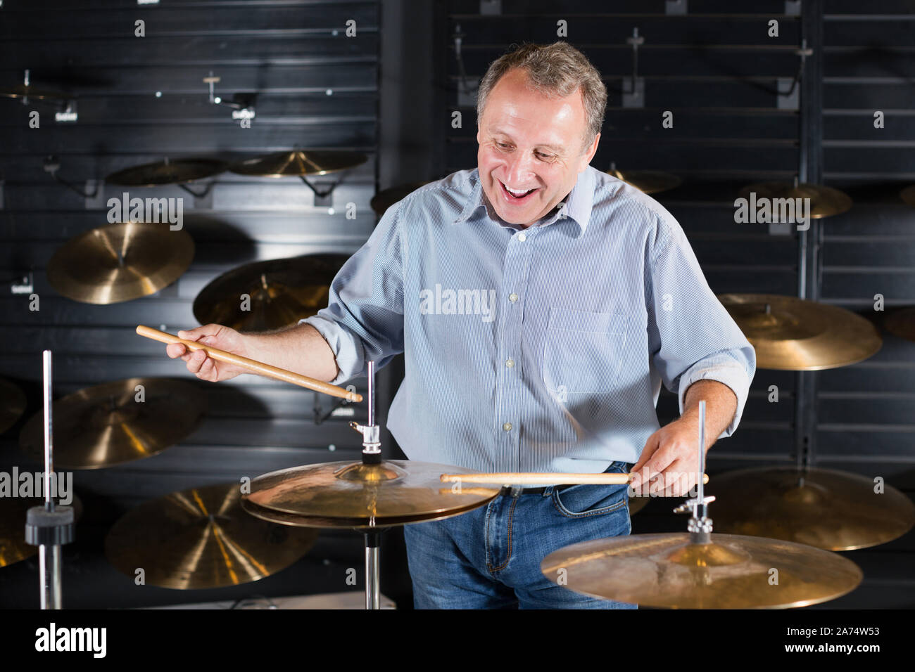 happy man is playing on drum set and satisfied it in music store Stock ...