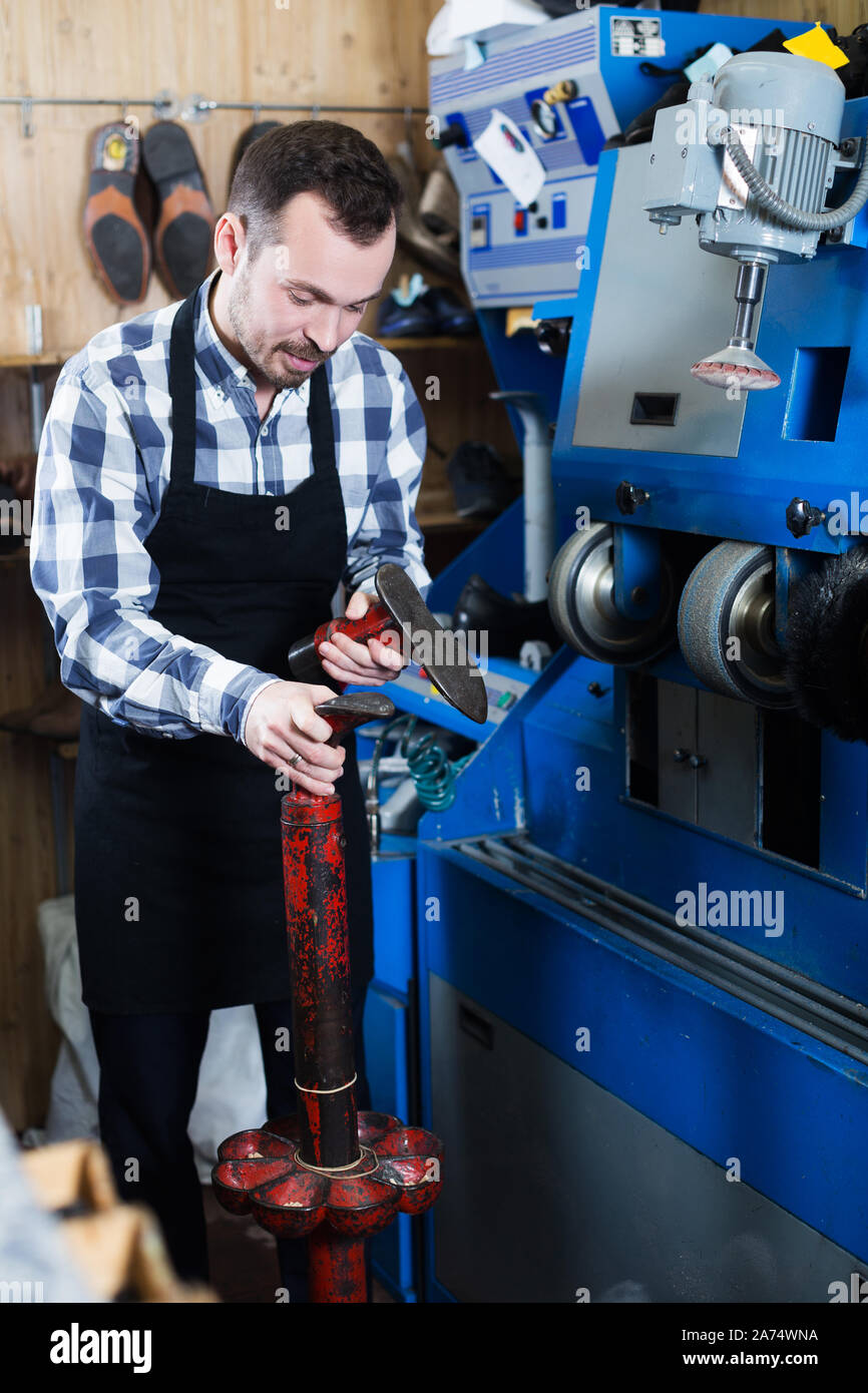 Adult male worker repairing shoe in specialized workshop Stock Photo ...
