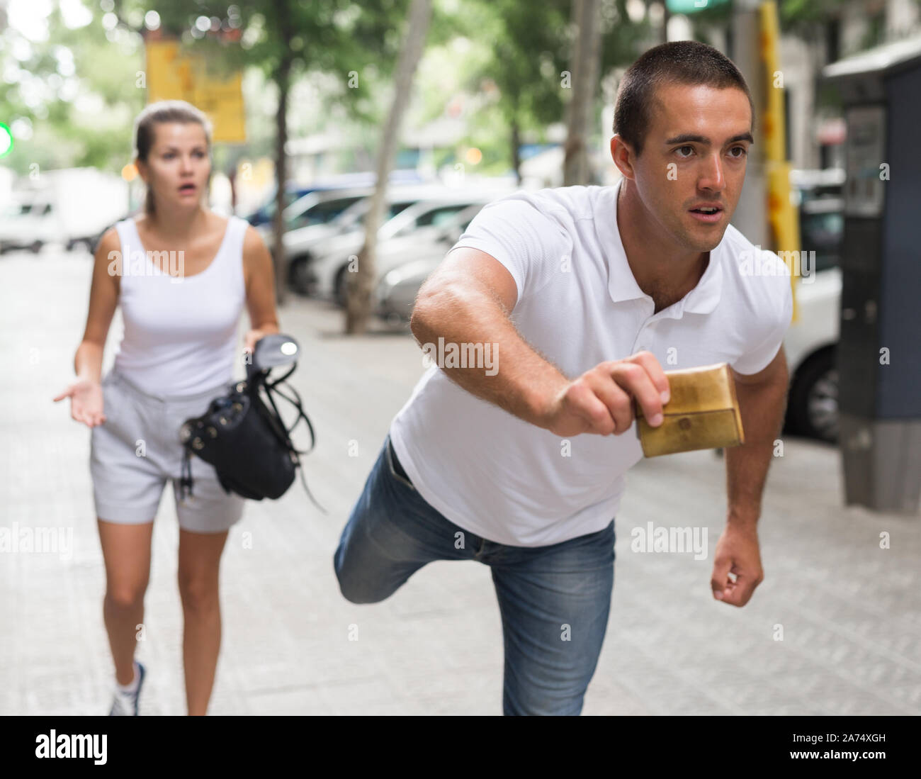 Male thief stealing purse from scared woman on street Stock Photo - Alamy