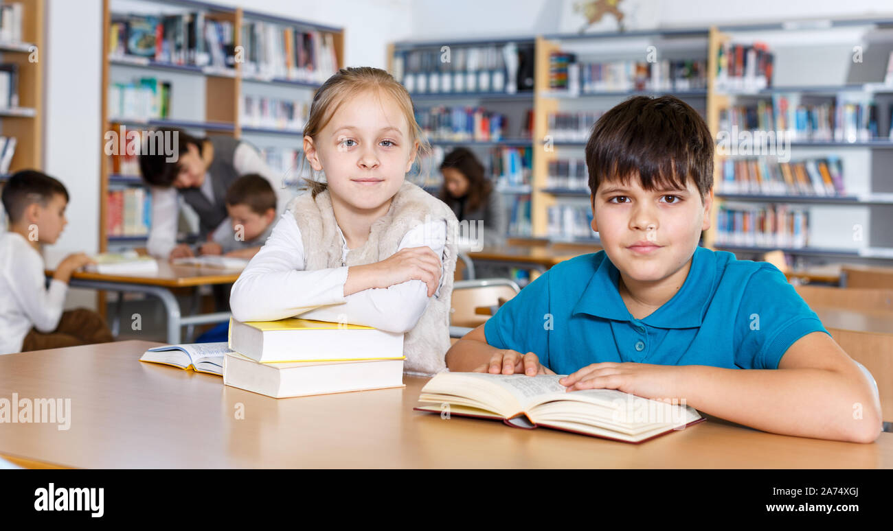 Cute tween girl and intelligent boy studying together in school library ...