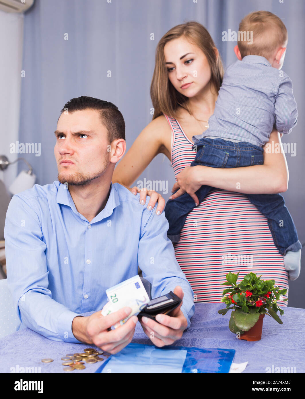 Angry female with child extorting money from male with hate indoors ...