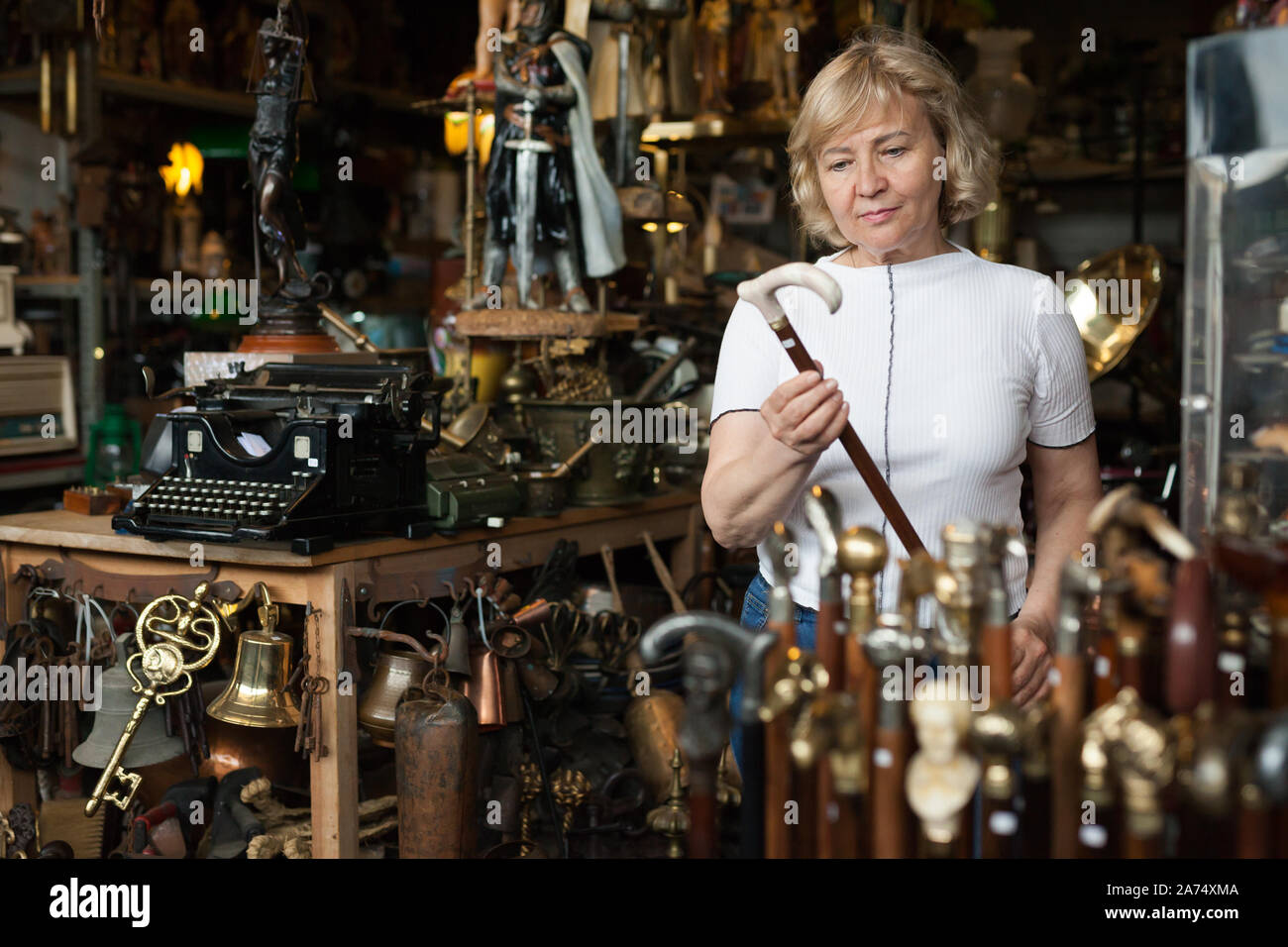 Senior woman chooses rare walking stick at flea market Stock Photo - Alamy