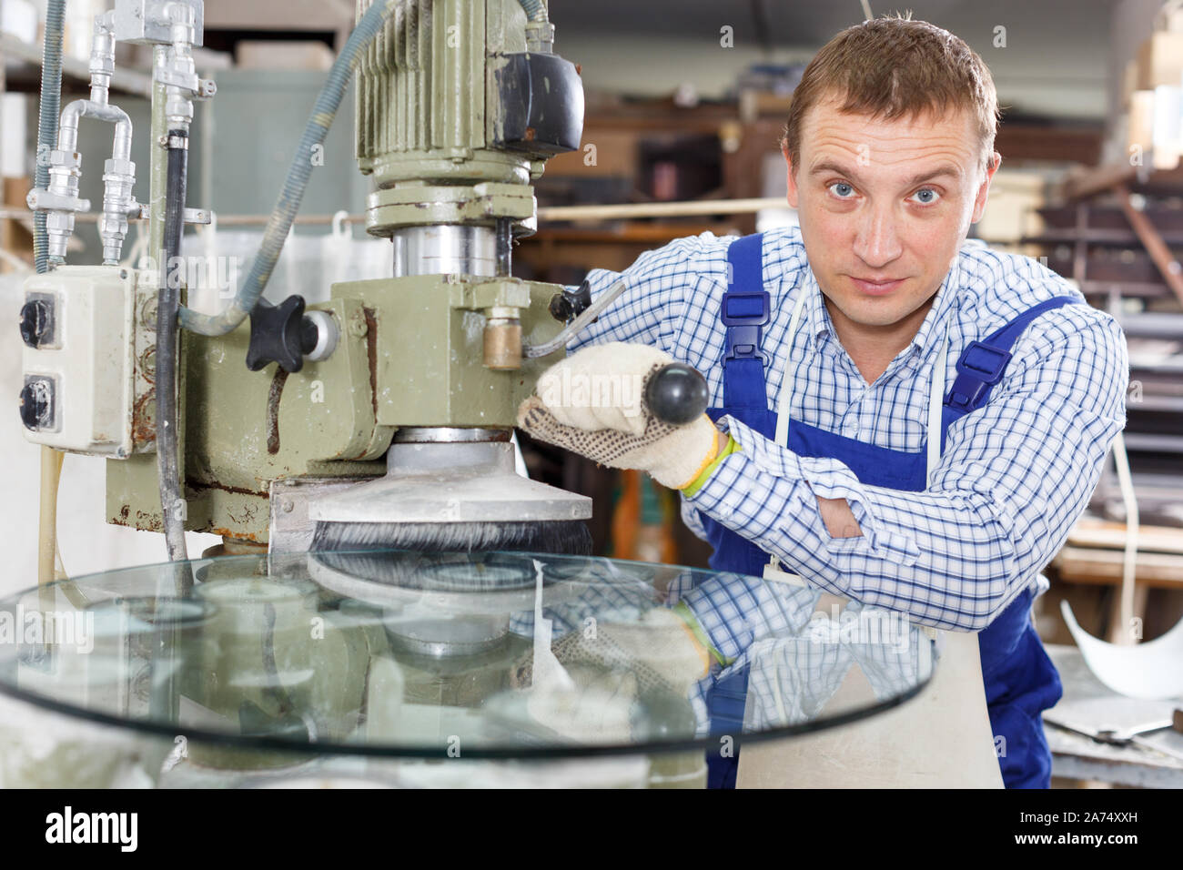 Experienced male worker of glass factory engaged in processing of ...