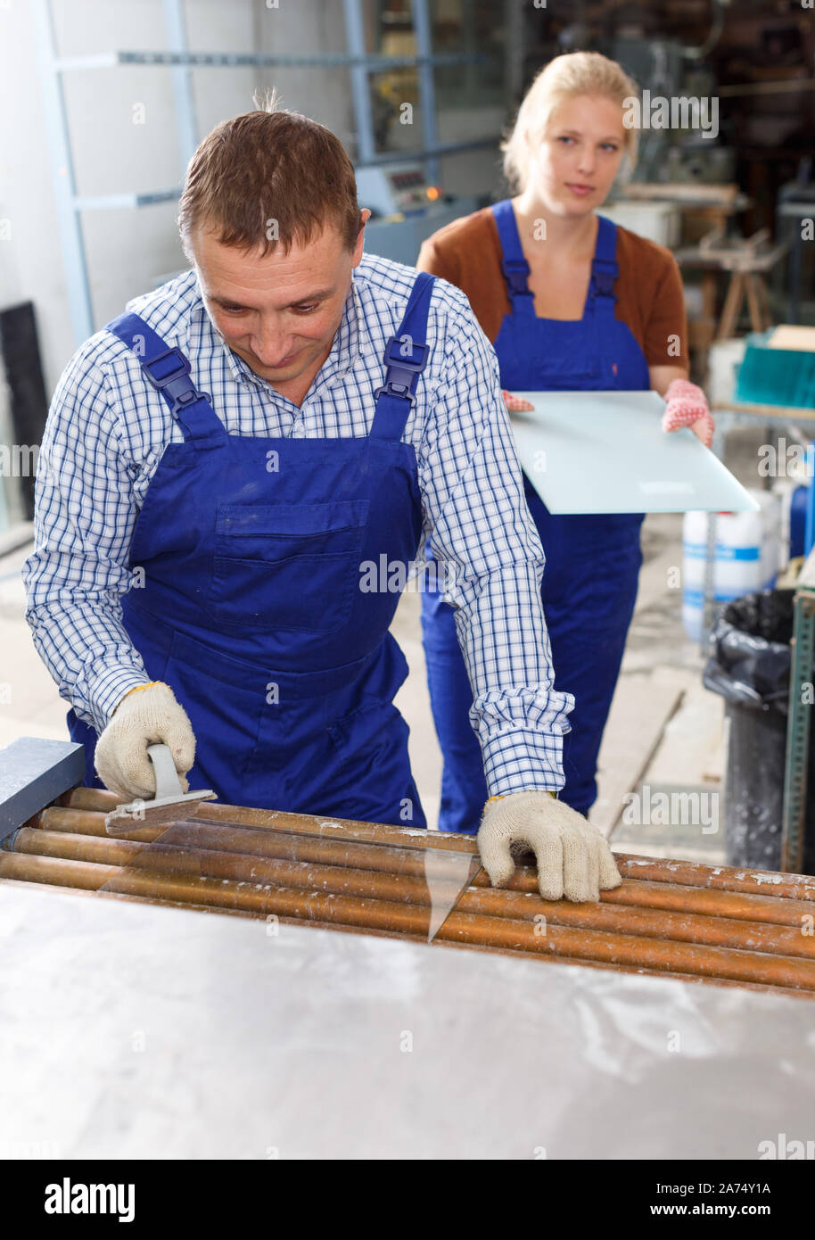 Experienced male glazier with female assistant working on stationary ...