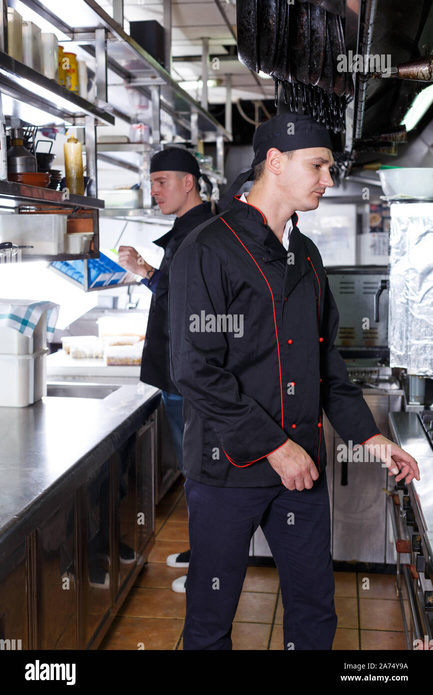 Positive cooks in process of working in kitchen of restaurant Stock ...