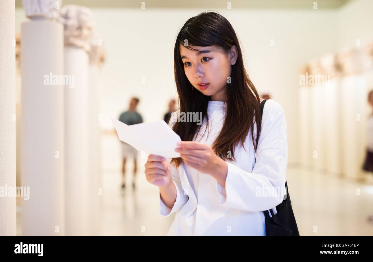 Portrait of young chinese woman with guide looking at exhibition in ...