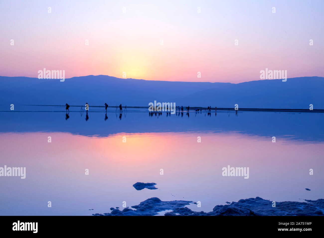 A group of photographers taking pictures of sunrise on the shore of the ...