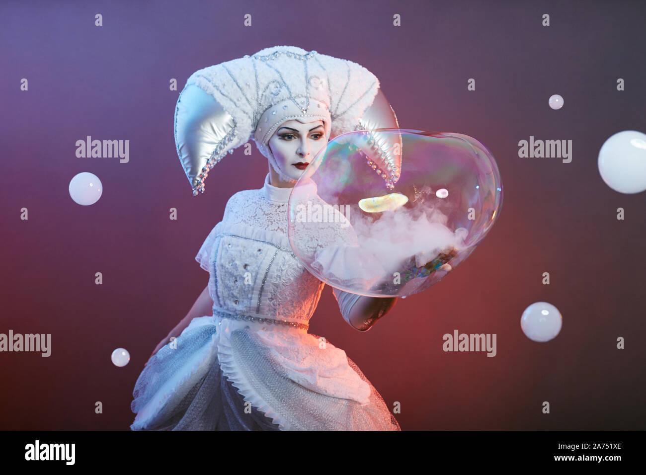 Circus performer magician shows tricks with soap bubbles. A woman and a ...