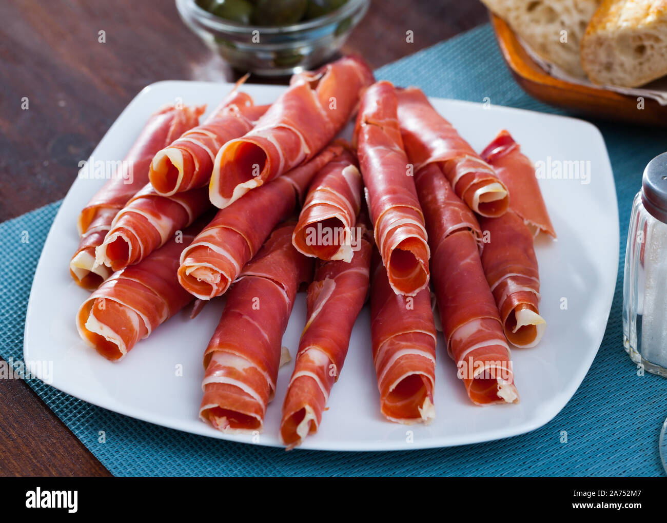 Traditional Spanish meal - rolls of iberian jamon served at plate ...