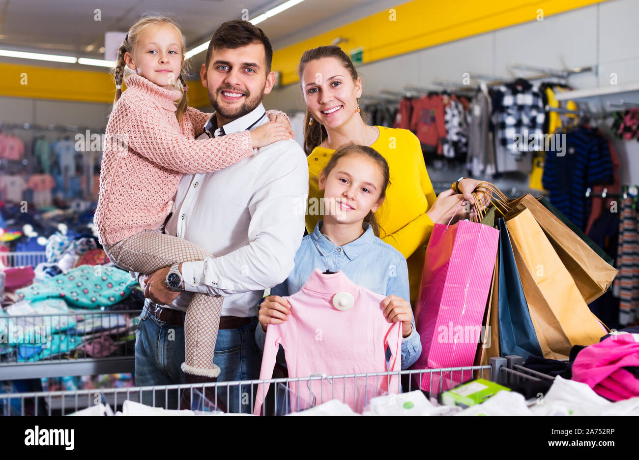 Young cheerful family with two daughters after shopping in clothes ...