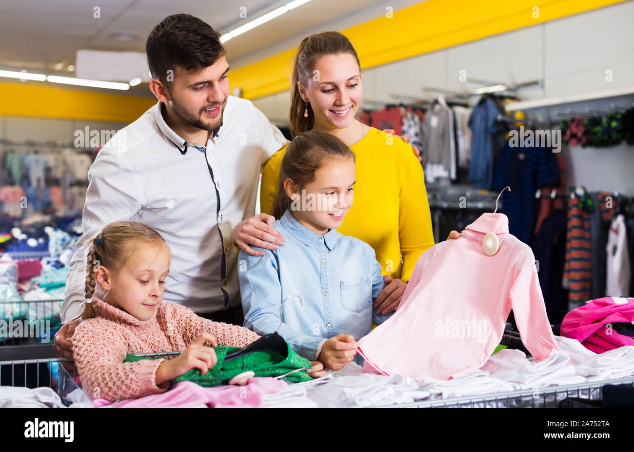 Young family of four looking for children clothes on shelves in store ...