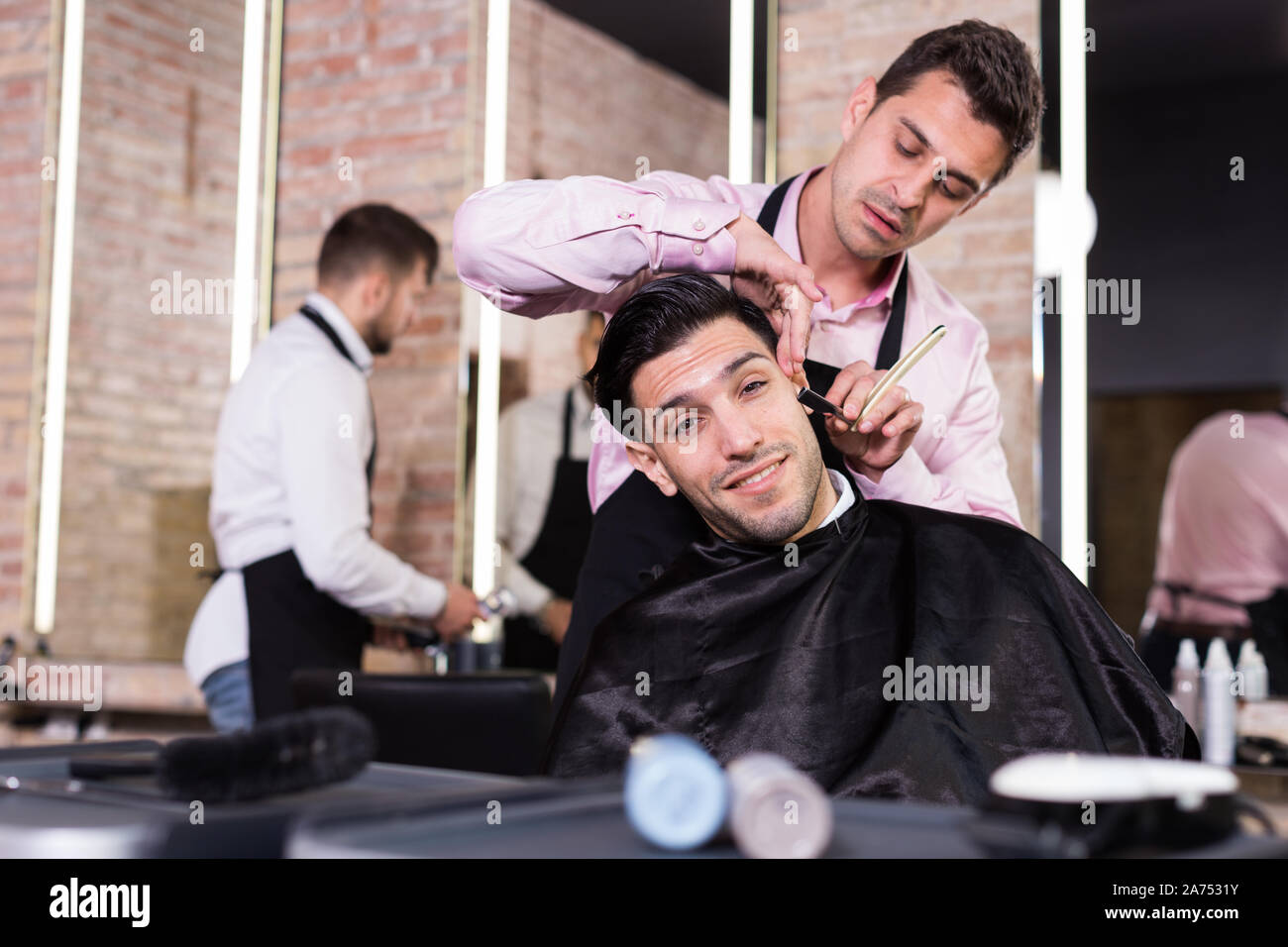 Male client getting old-fashioned shave with straight razor from male ...