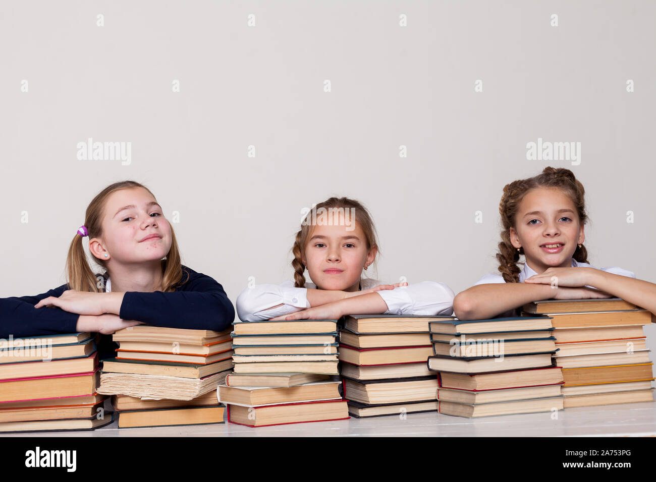 three girls with books in class at a desk at school Stock Photo - Alamy