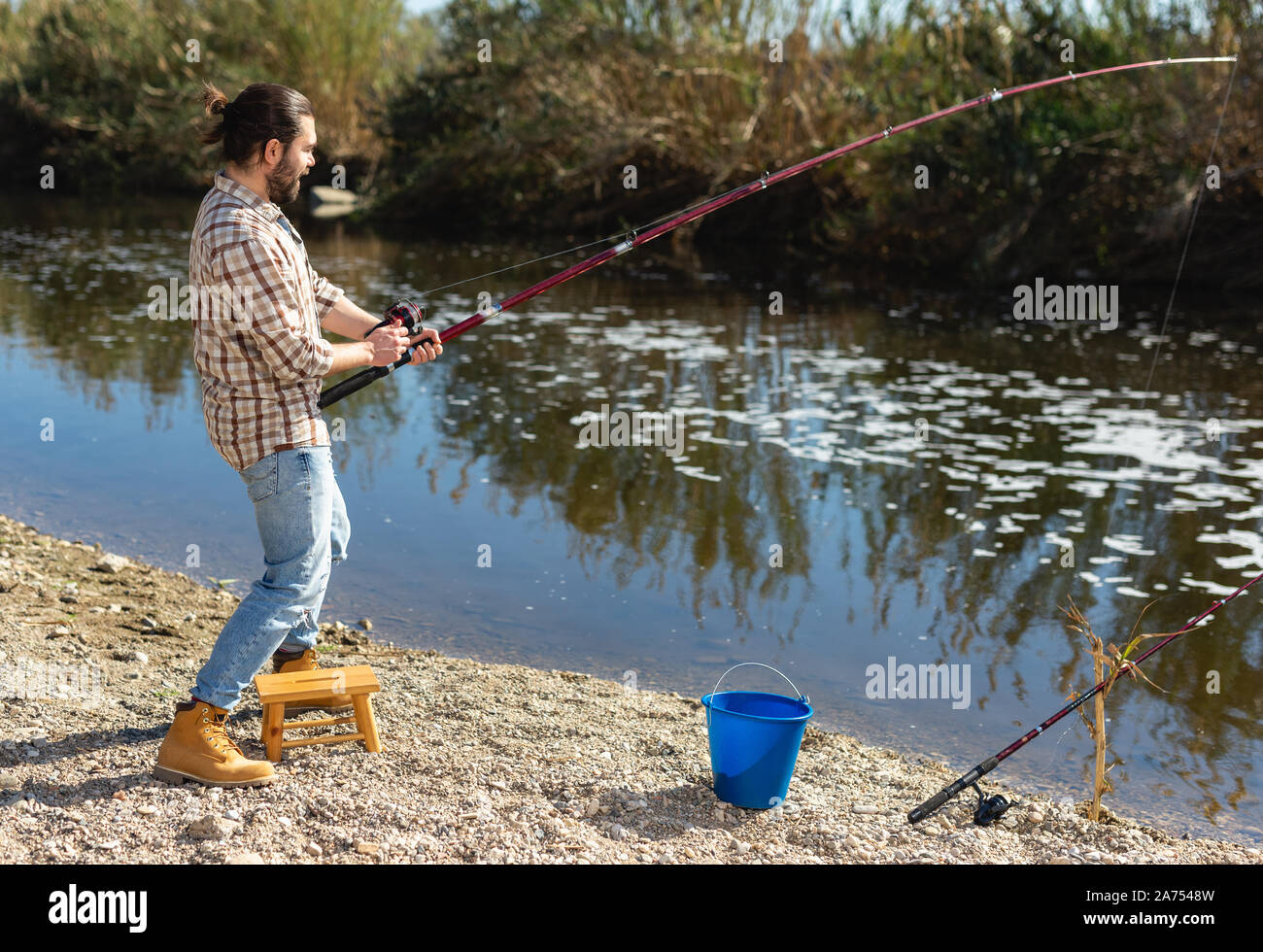 Happy fisherman pulls fish out of the river Stock Photo - Alamy