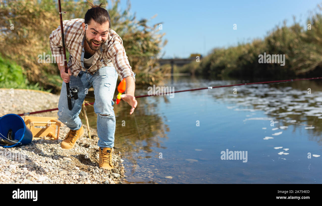 Happy fisherman pulls fish out of the river Stock Photo - Alamy