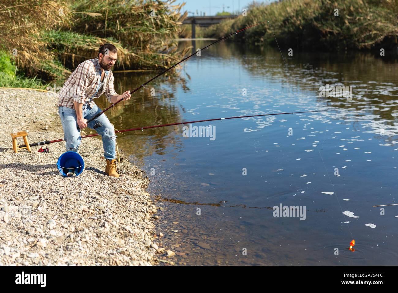 Happy fisherman pulls fish out of the river Stock Photo - Alamy