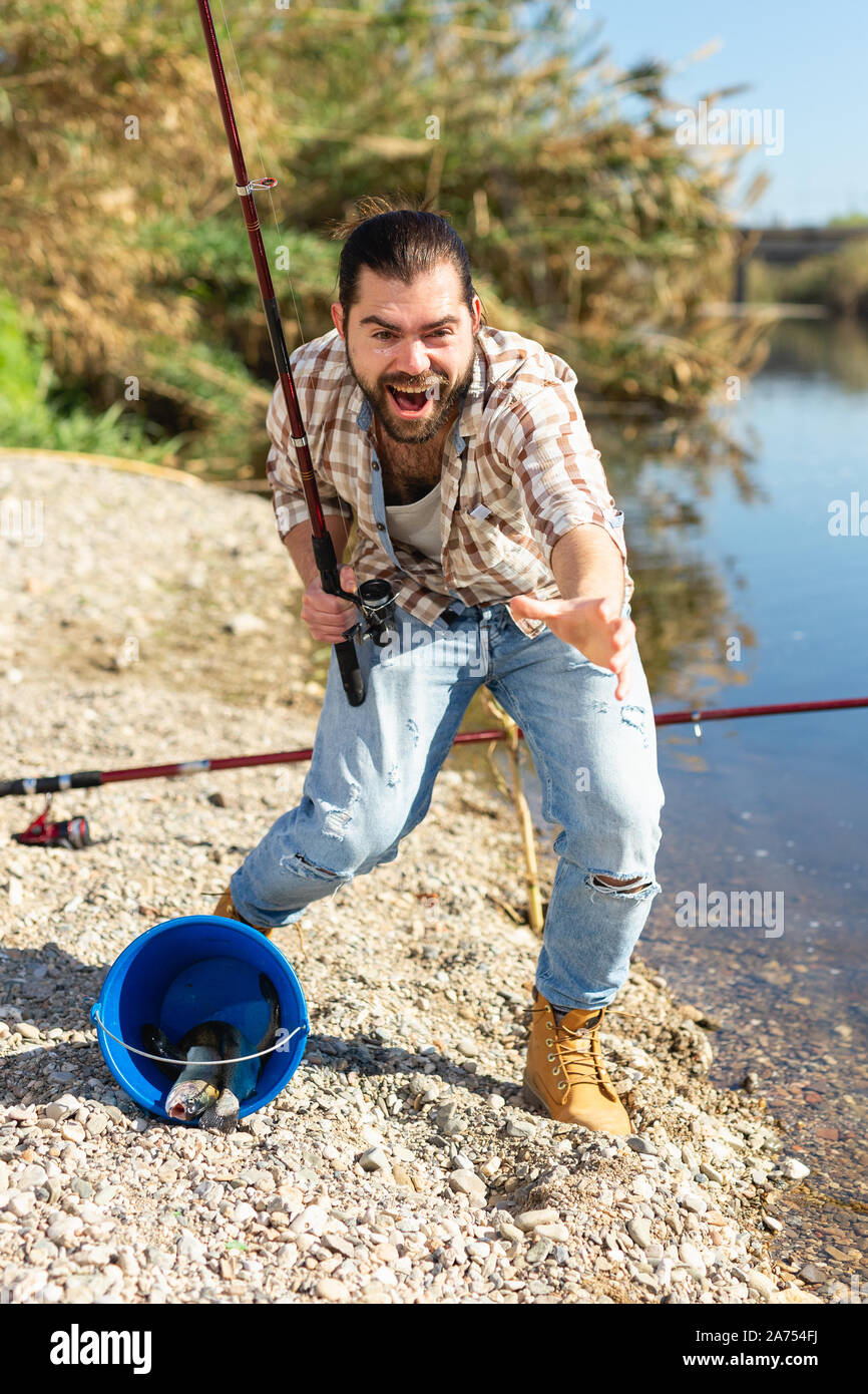 Happy fisherman pulls fish out of the river Stock Photo - Alamy