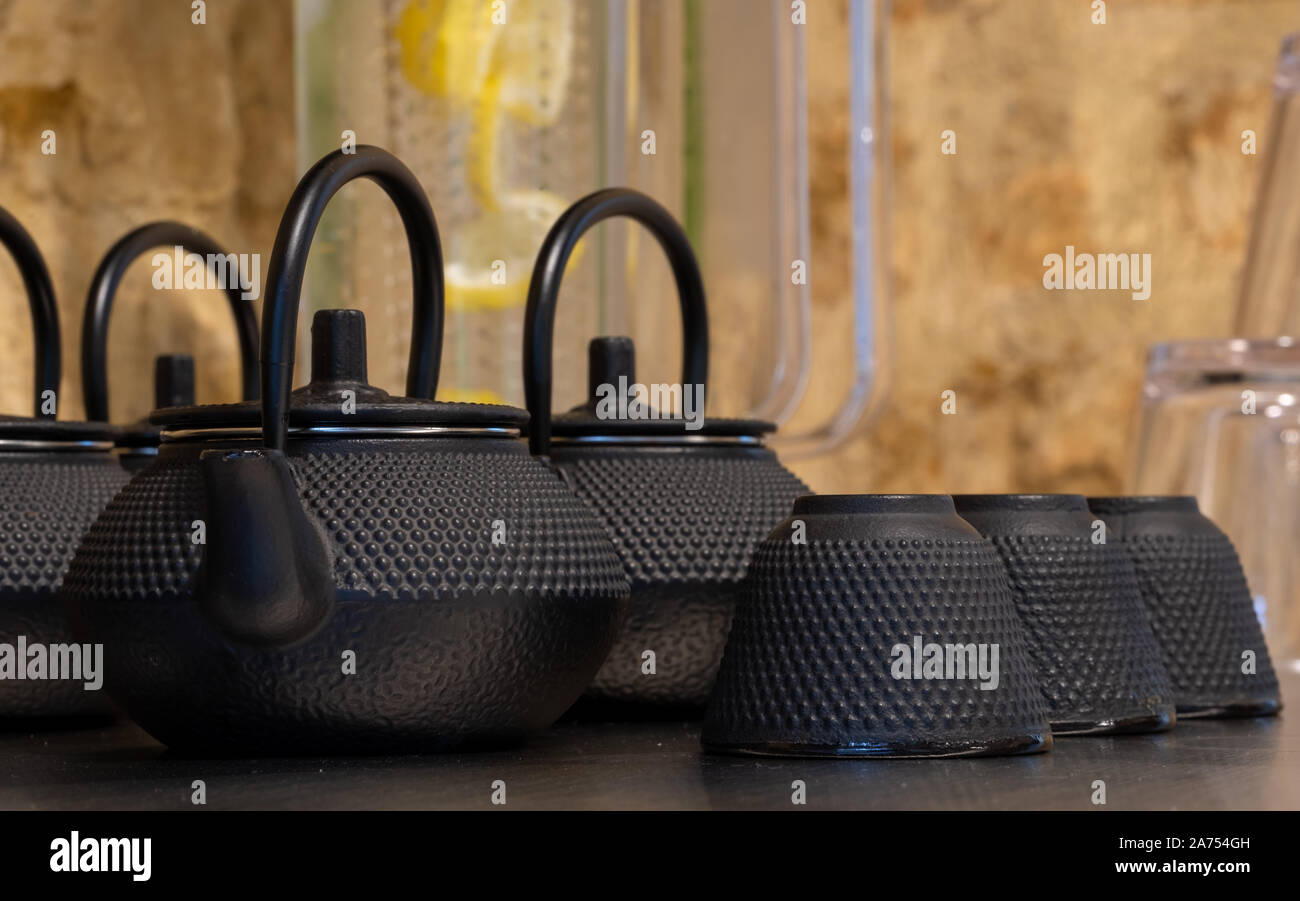 Close up of black textured cast iron Asian style tea pots with handles ...