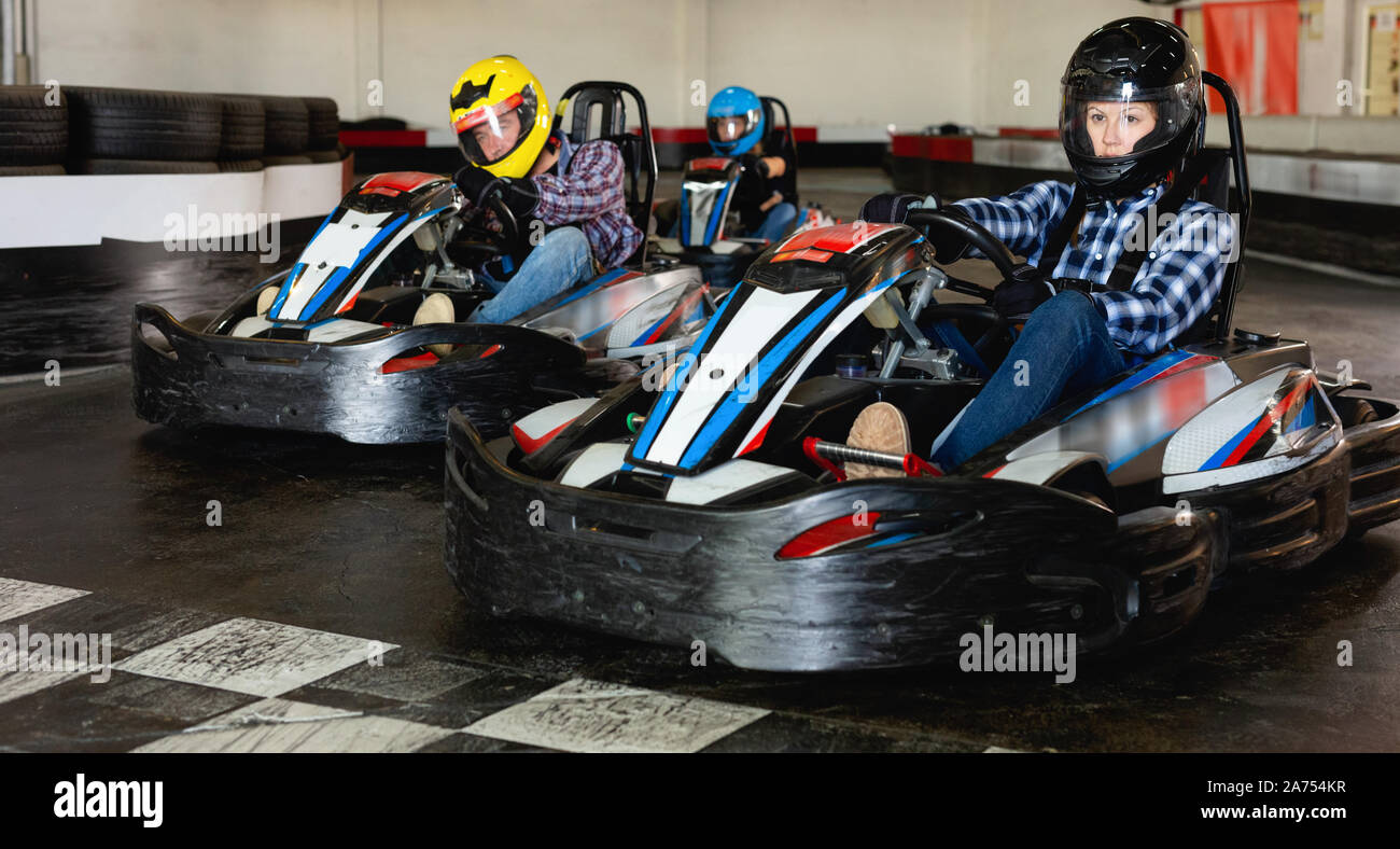 Group of glad smiling people driving go-carts at racing track Stock ...