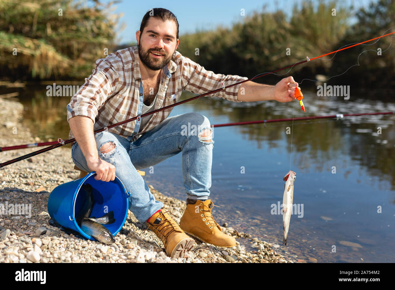Positive fisherman holding catch freshwater fish in hands Stock Photo ...