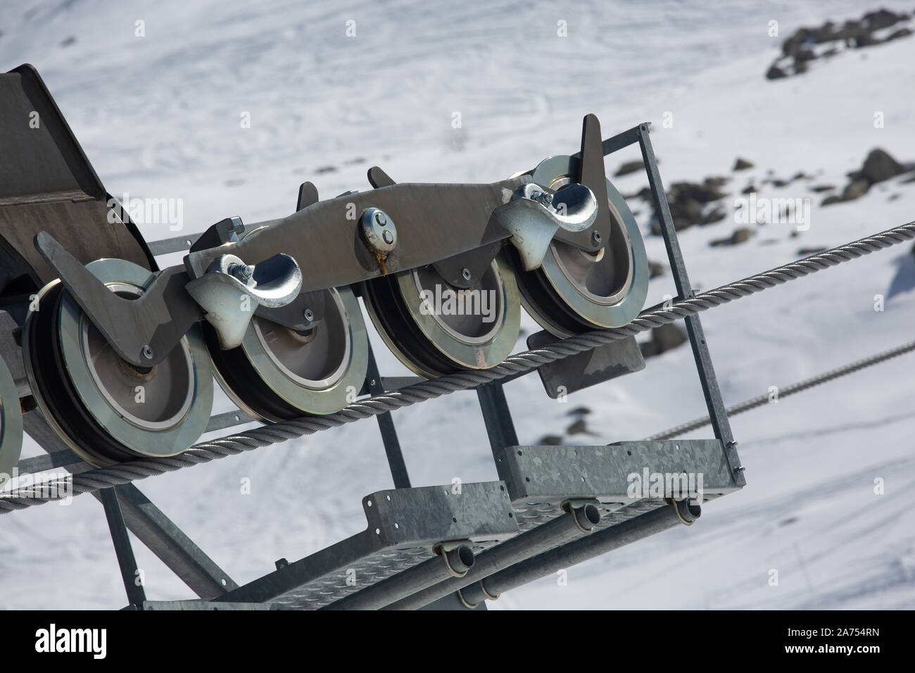 Wheels and metal cable of modern ropeway on snowy mountain slope on ski ...