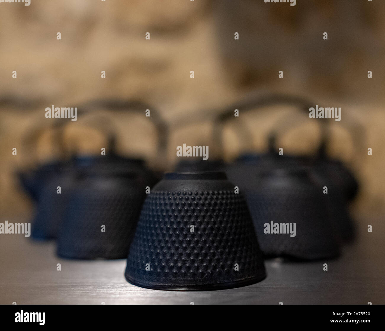 Close up of black textured cast iron Asian style tea pots with handles ...