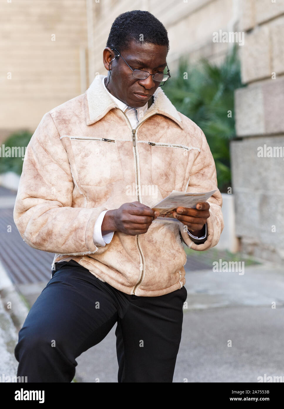Positive mature African man reading guidebook near Art Museum Stock ...