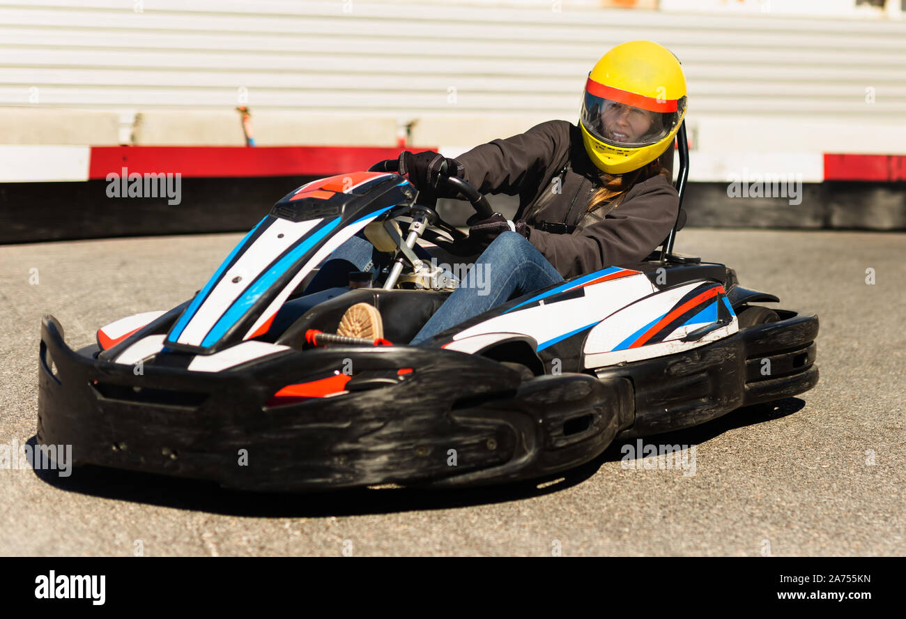 Portrait of girl in helmet driving kart at a racing track outdoors ...