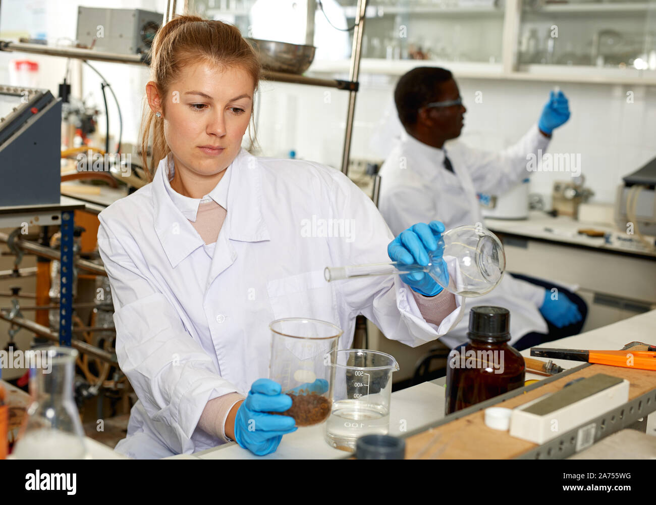 Focused woman lab technicians in glasses working with reagents and test ...