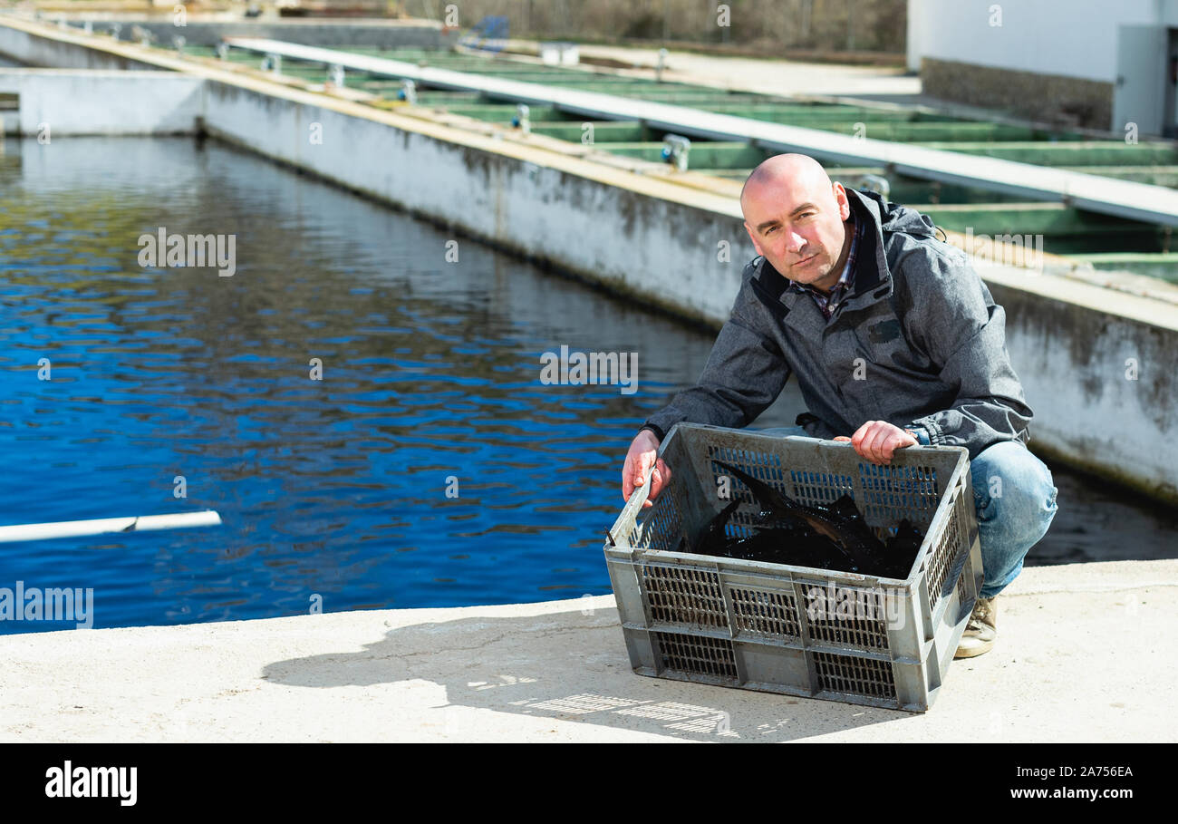Portrait of man fish farm worker demonstrating sturgeon Stock Photo - Alamy