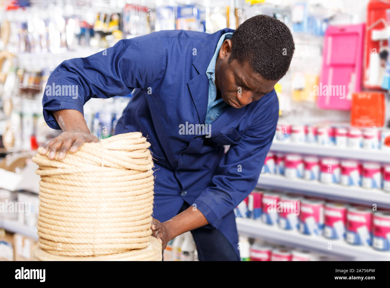 adult seller of household goods shop organizing assortment of items on ...