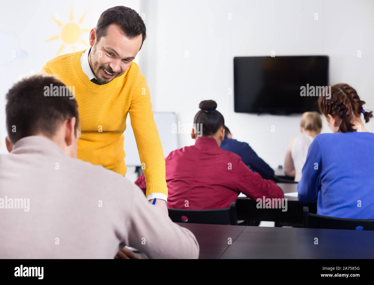 Teacher explaining a difficult problem to student during test at a ...