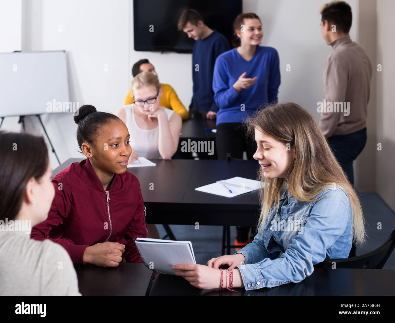 glad classmates having animated talks at break between classes sits by ...