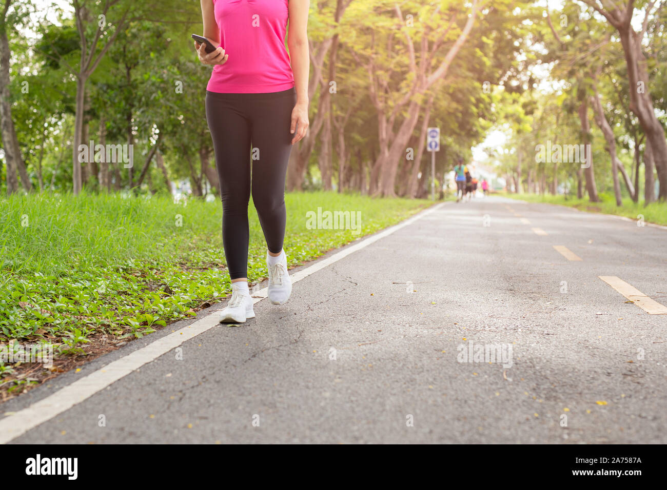 Fitness woman exercise walking on park trail with hand holding cell ...