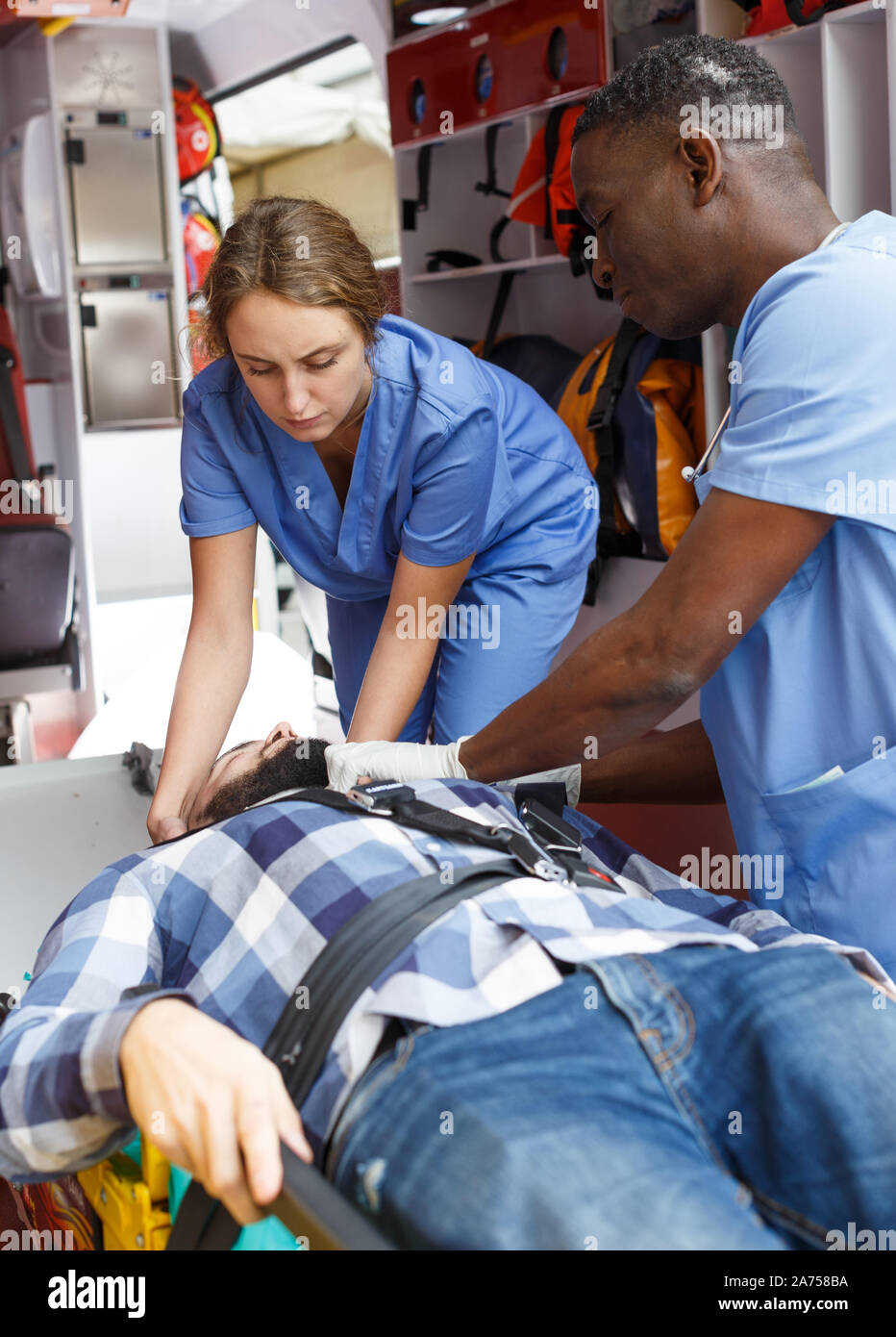 Emergency doctors fixing patient on stretcher in ambulance car Stock ...