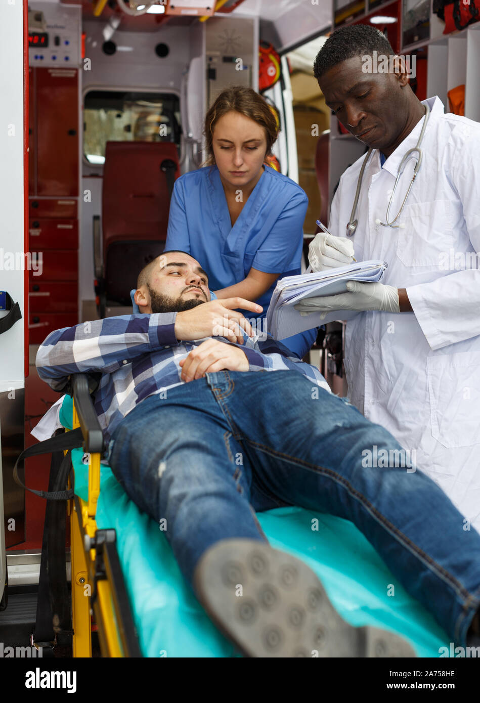Emergency doctor asking patient to sign in logbook at ambulance car ...