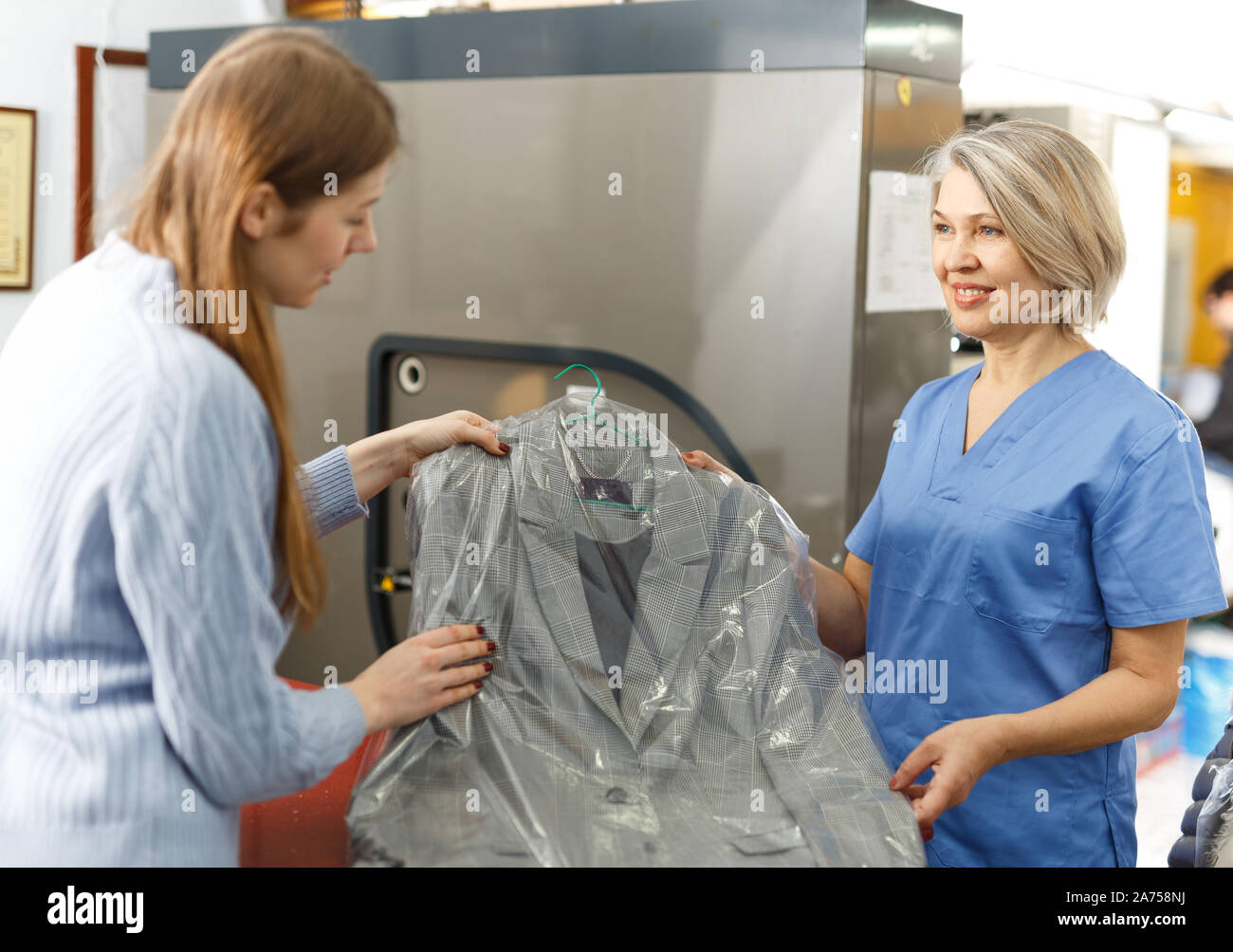 Female client receiving her clean clothes at dry-cleaning salon Stock ...