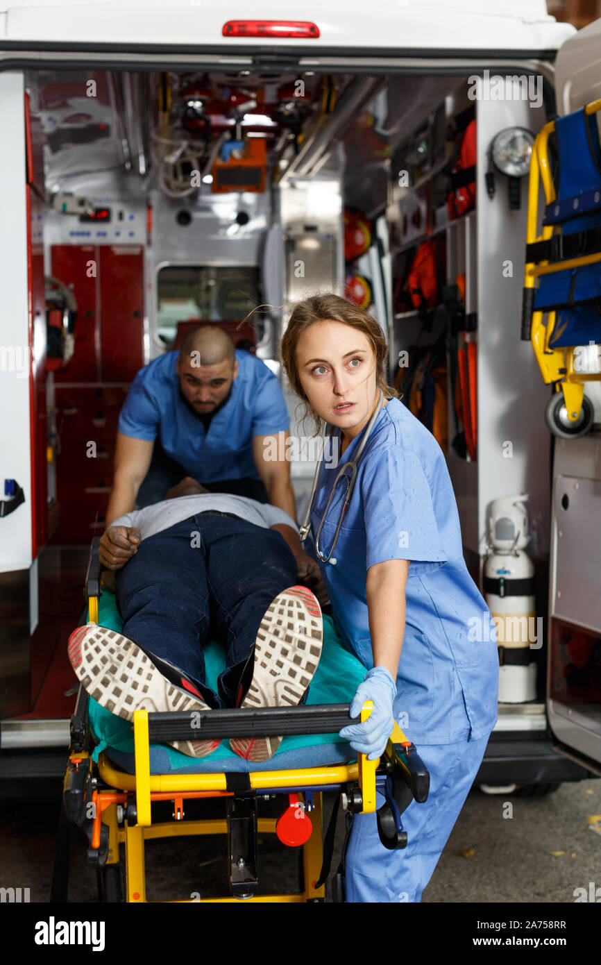 Emergency doctors fixing patient on stretcher in ambulance car Stock ...