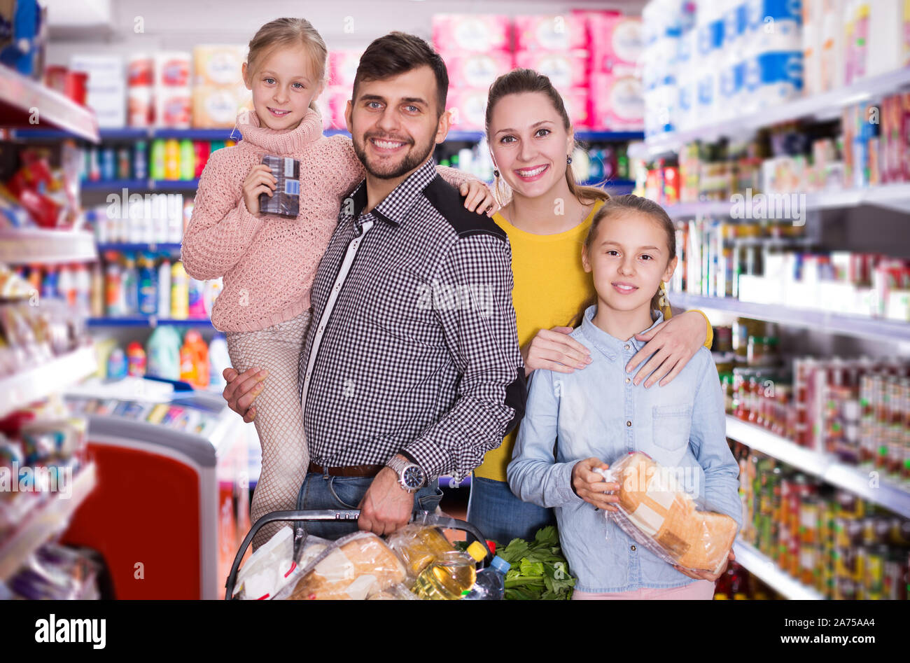 glad young parents with two little girls with purchases during family ...