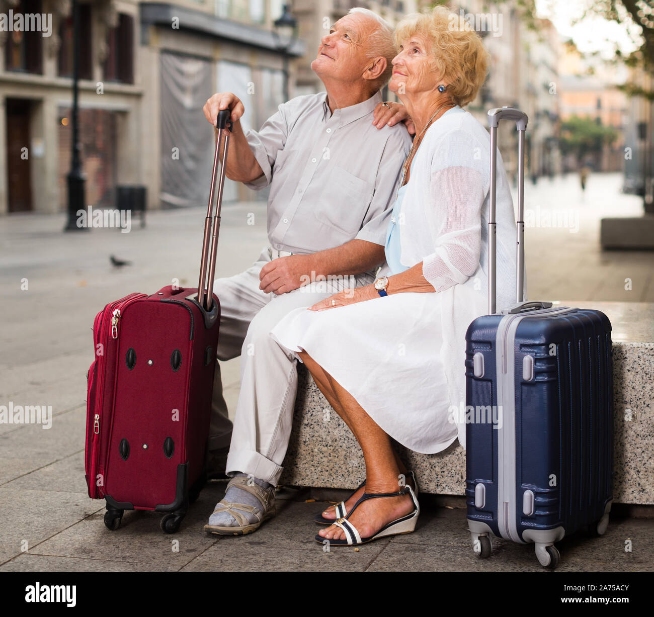 Happy loving mature spouses enjoying joint vacation sitting on bench ...