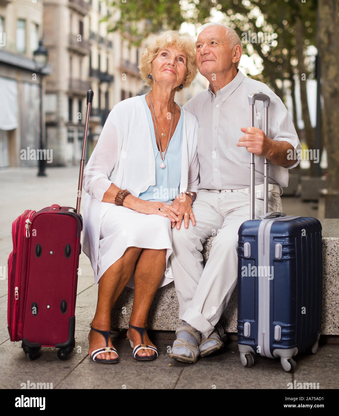 Happy loving elderly spouses enjoying joint vacation sitting on bench ...