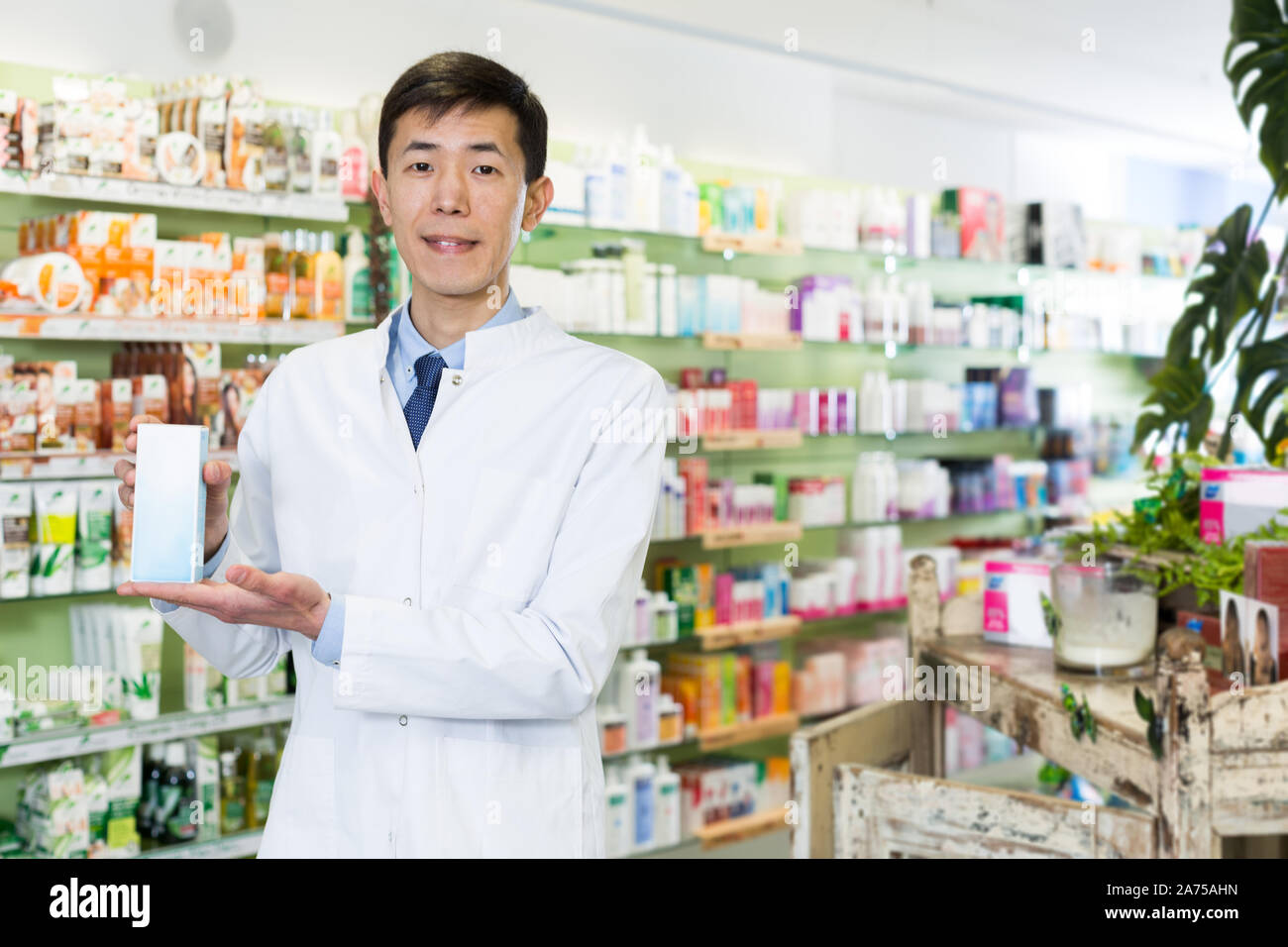 Positive chinese male pharmacist is posing with medicines in medical ...
