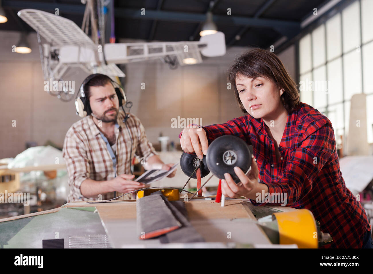 Female aircraft enthusiast engaged in creating plane models in workshop ...