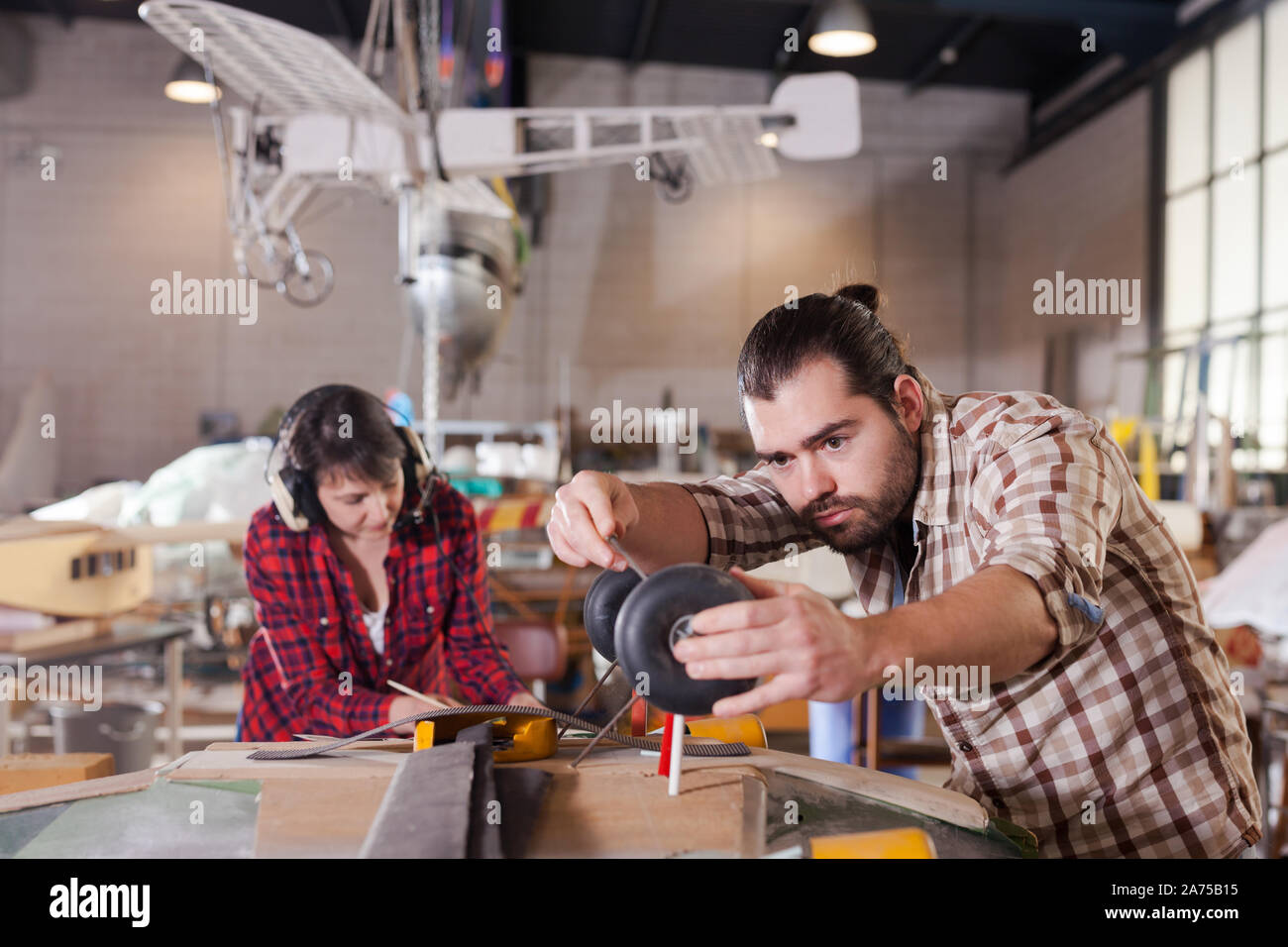 Young male hobbyist engaged in creating plane models in aircraft ...