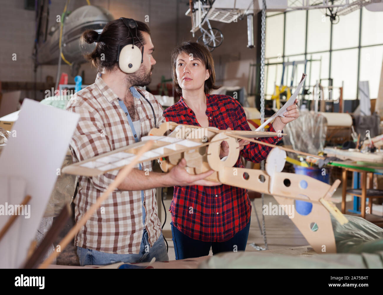 Female and male hobbyists engaged in creating plane models in aircraft ...